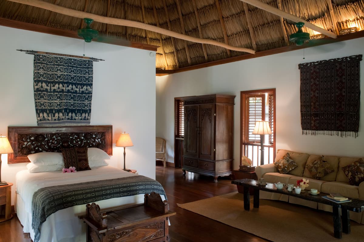 Quarto tradicional com cama, um armário de madeira, um sofá e uma mesa.