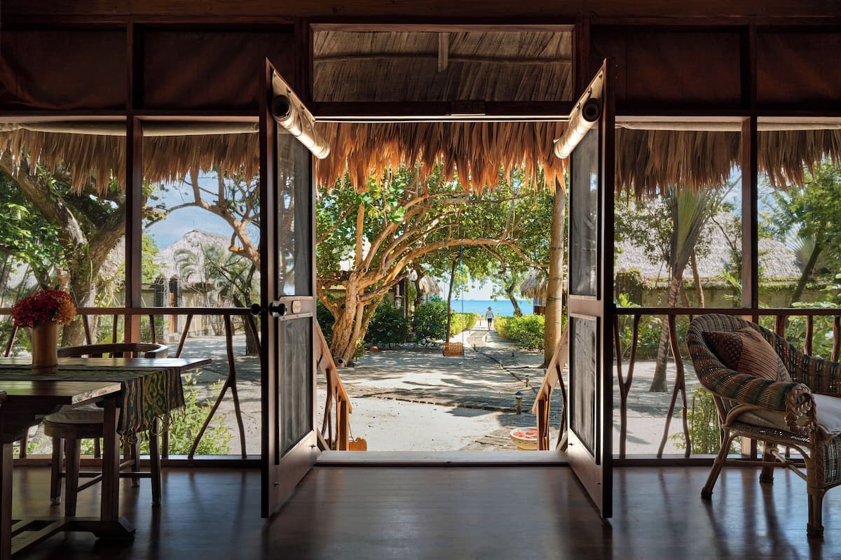 Quarto amplo com vista para uma trilha arborizada que leva à praia.
