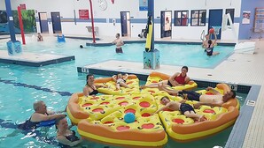 Piscina interna com várias pistas e boias infláveis.