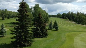 Um campo de golfe com fairways bem cuidados, bunkers de areia e um mastro de sinalização.