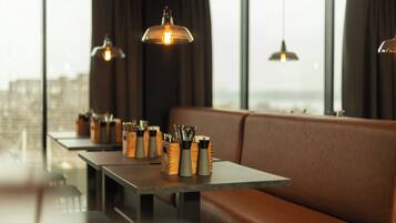 Um restaurante moderno com assentos de couro, mesas de madeira e iluminação pendente.
