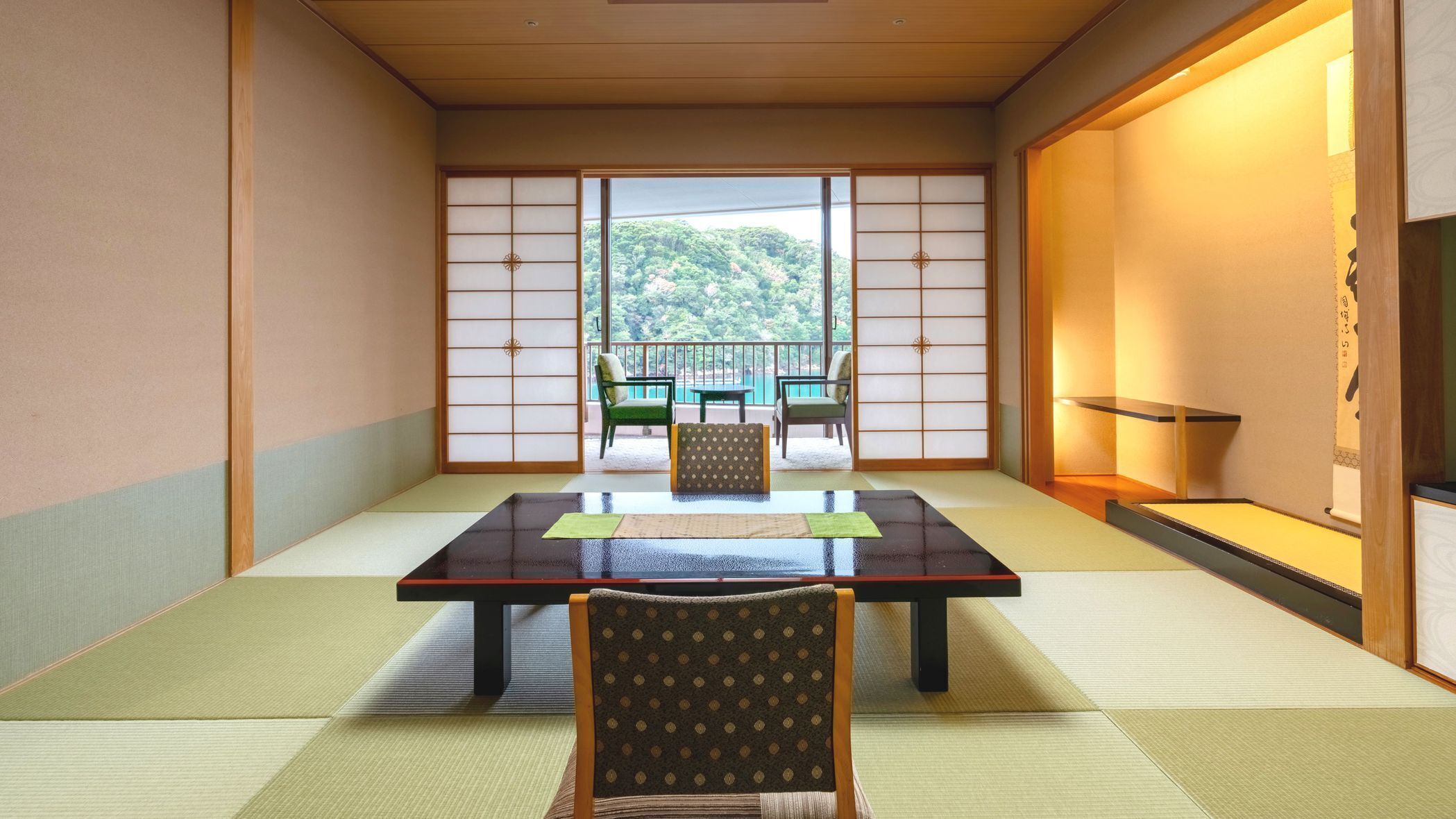 Quarto japonês tradicional com tatames, uma mesa baixa e vista para uma varanda com cadeiras.