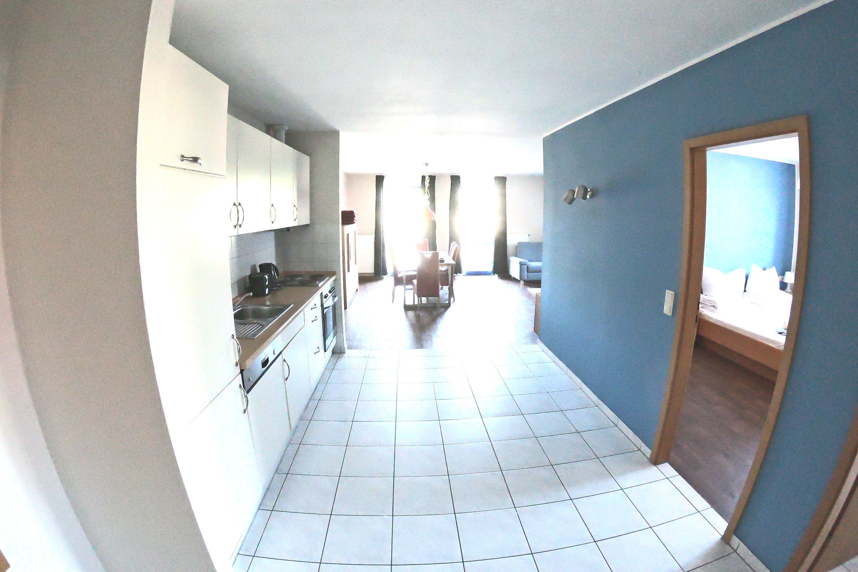 Um corredor estreito com cozinha à esquerda e sala de estar à direita.