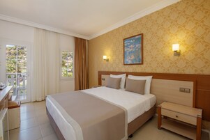 Quarto de hotel com uma cama grande, uma escrivaninha e vista para o exterior.