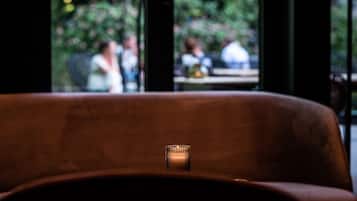 Vista da janela com uma vela sobre a mesa, cena externa desfocada com pessoas.