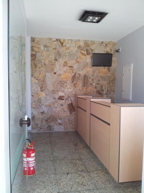 Casa de banho pequena e moderna, com parede de pedra, pia e extintor de incêndio.
