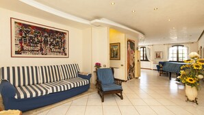 Uma sala de estar ampla com um sofá listrado, uma poltrona azul e uma grande pintura na parede.