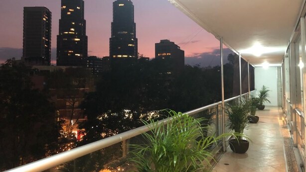 Uma varanda com vista para edifícios da cidade ao anoitecer.