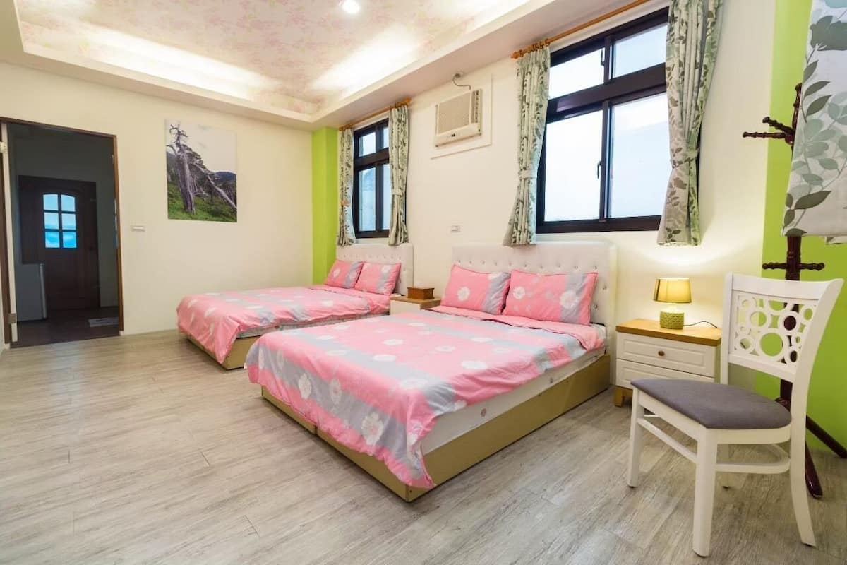 Quarto com duas camas, uma escrivaninha e uma cadeira.
