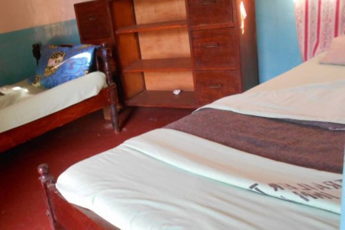 Quarto com uma cama de solteiro, cômoda de madeira e parede azul.