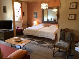 Quarto de hotel com cama, televisão, candeeiro, cadeira e mesa.