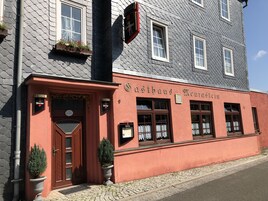 Um edifício com fachada vermelha e uma placa com a inscrição 'Gasthof Meurestein'.