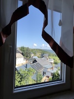 Janela com vista para uma área residencial, incluindo casas e árvores.