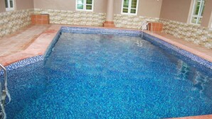 Piscina interior com borda azulejada e superfície de água azul transparente.