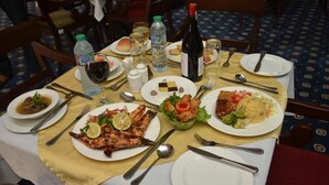 Mesa posta com pratos de comida, talheres e bebidas.