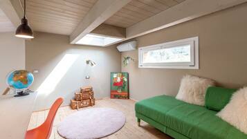 Um quarto com um sofá verde, um globo, uma pintura e piso de madeira.