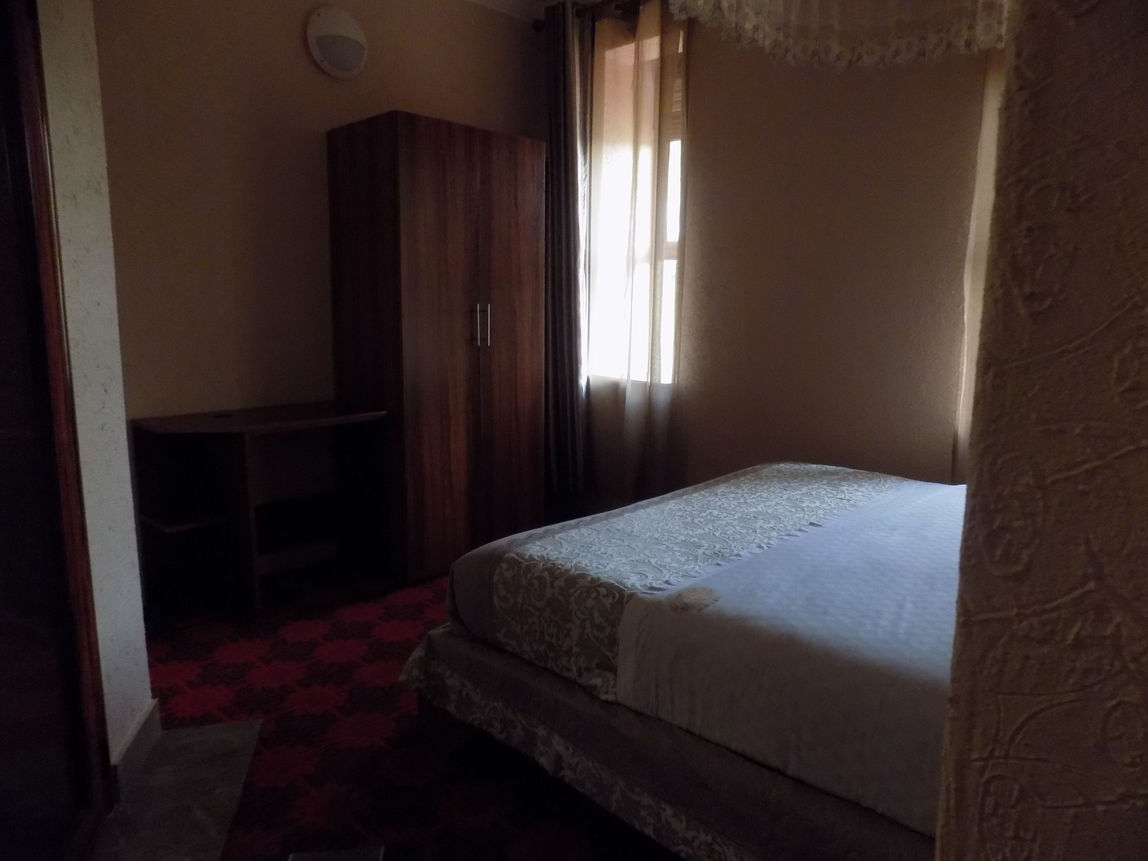Um quarto com uma cama, um guarda-roupa e uma escrivaninha.