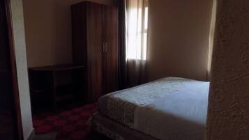 Um quarto com uma cama, um guarda-roupa e uma escrivaninha.