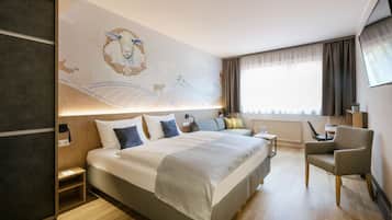 Quarto de hotel moderno com uma cama grande, uma escrivaninha, uma cadeira e um janelão com cortinas.