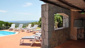 Área da piscina com espreguiçadeiras e um muro de pedra.