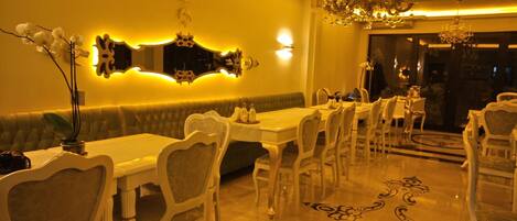 Uma sala de jantar com uma mesa comprida e cadeiras, um candelabro e um espelho decorativo na parede.