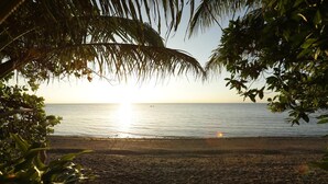 Cena de praia com vista clara do oceano e um barco ao longe.