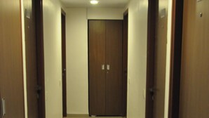 Um corredor com portas de madeira em ambos os lados, chão de azulejos e uma luminária no teto.