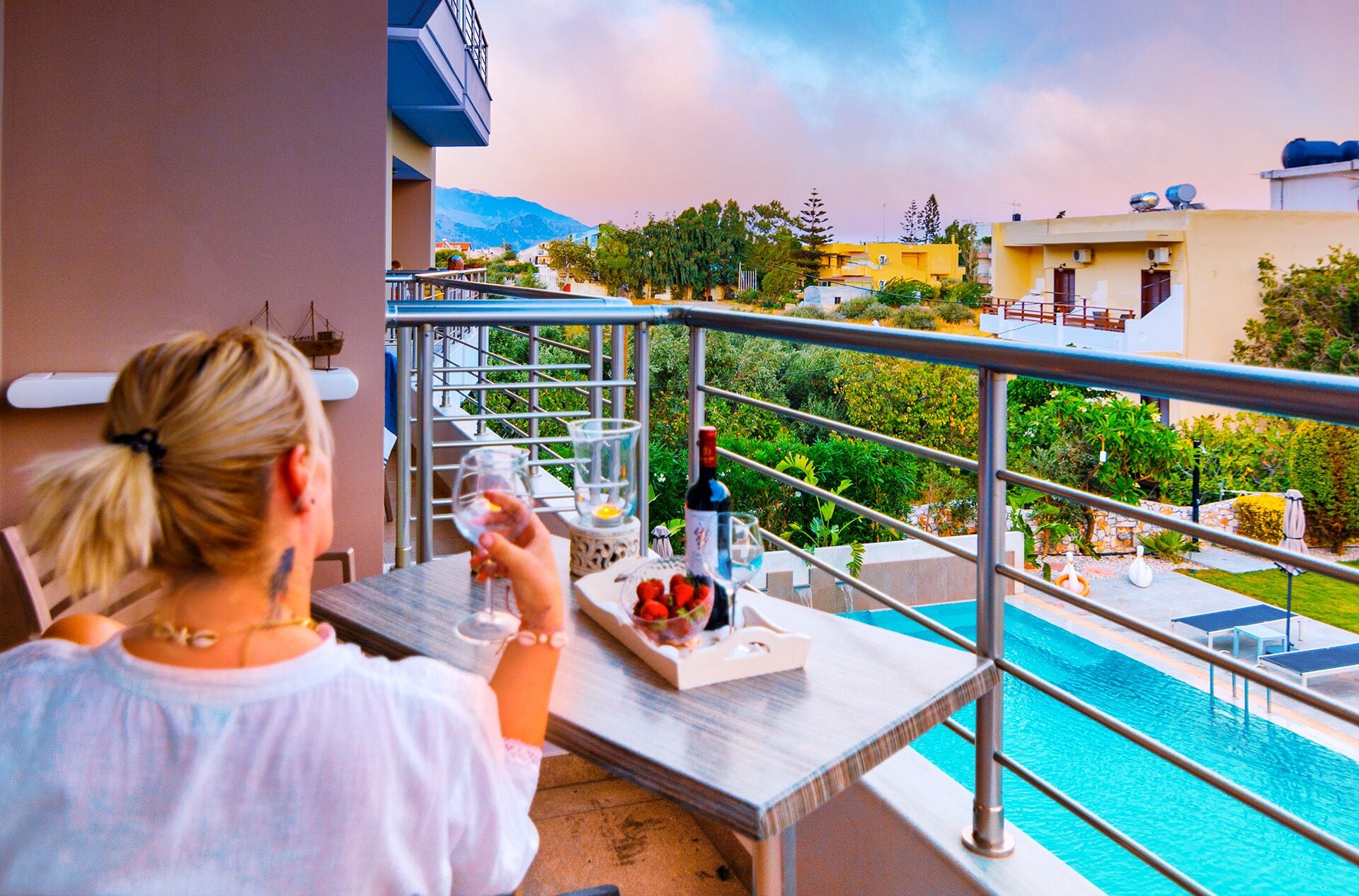 Uma varanda com piscina, uma mesa com taças de vinho e uma garrafa.