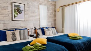 Quarto de hotel com duas camas, paredes de madeira, um quadro emoldurado, mesa de cabeceira com abajur e janela com cortinas.