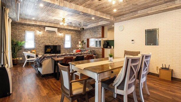 Uma sala de jantar ampla com mesa e cadeiras de madeira, parede de tijolos e ventilador de teto.