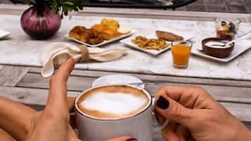 Uma mesa com uma xícara de café, pastéis e um copo de suco de laranja.