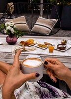 Uma mesa com uma xícara de café, pastéis e um copo de suco de laranja.
