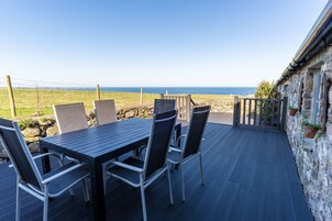 Um terraço com mesa e cadeiras de frente para o oceano.