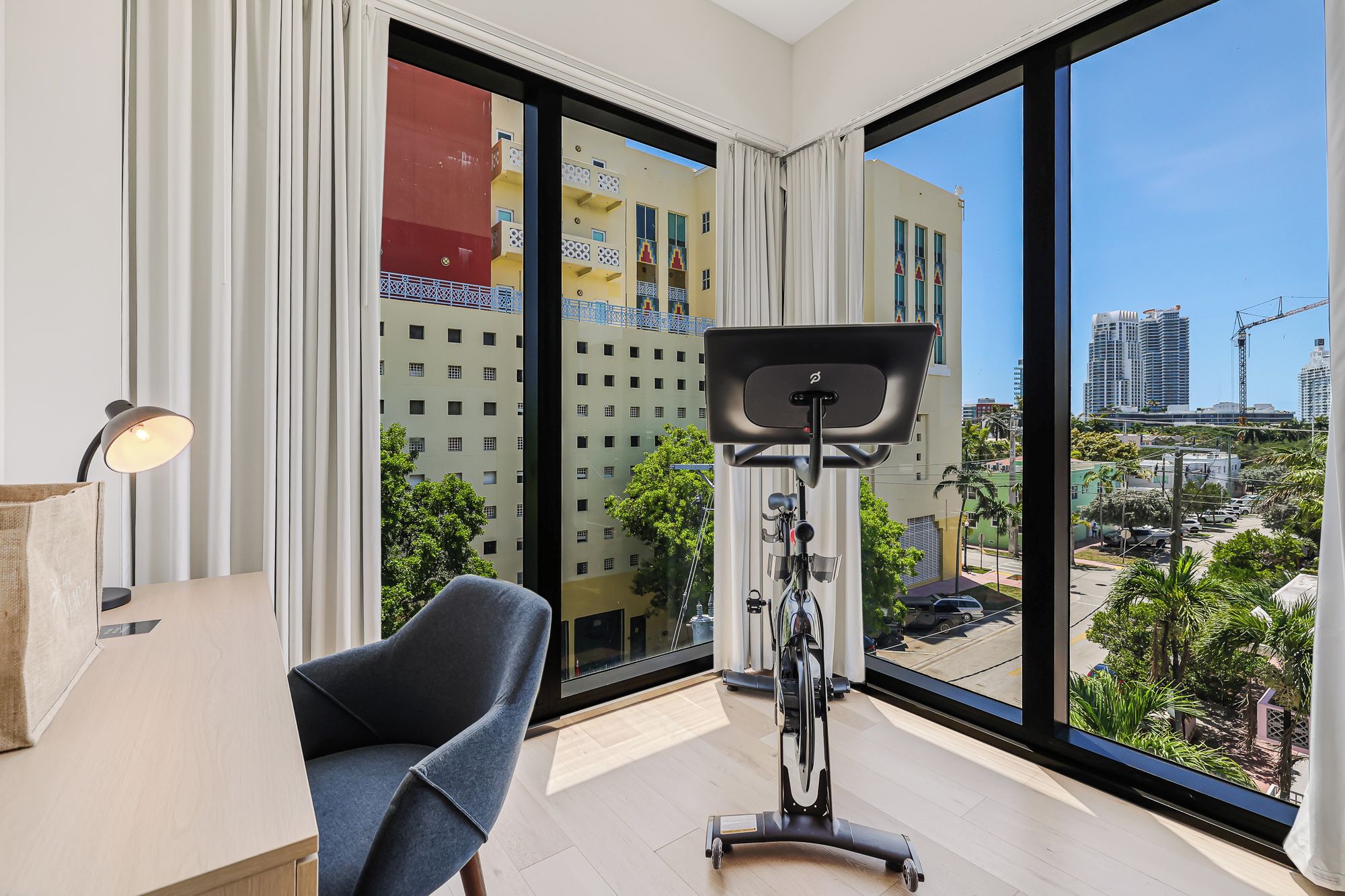 Quarto moderno com uma janela grande, bicicleta ergométrica e uma cadeira.