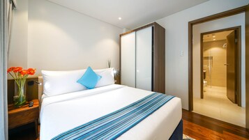 Quarto de hotel com cama, mesa de cabeceira, um vaso com flores e um espelho.