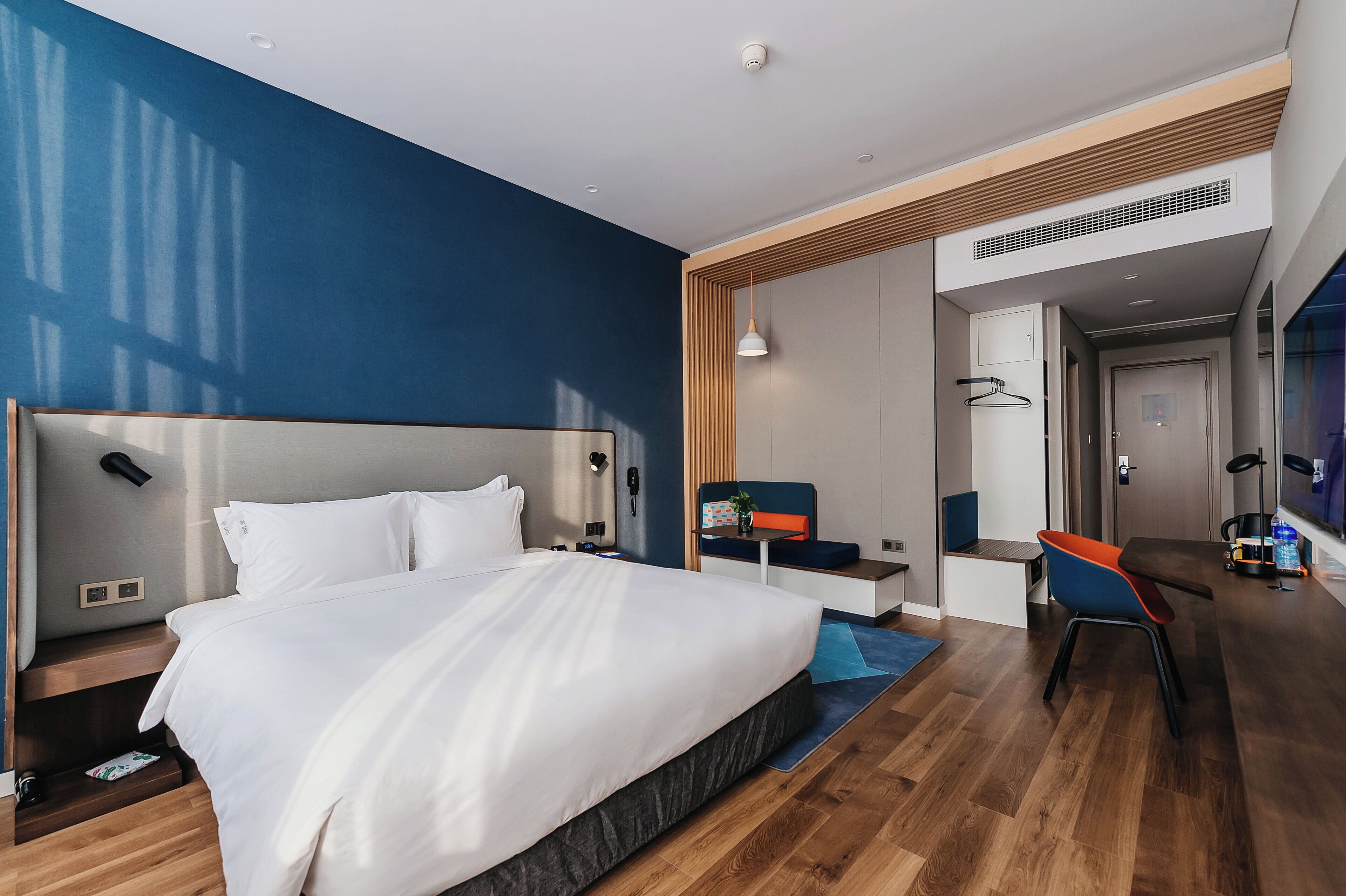 Quarto de hotel moderno com uma cama grande, uma escrivaninha e um espaço de estar.