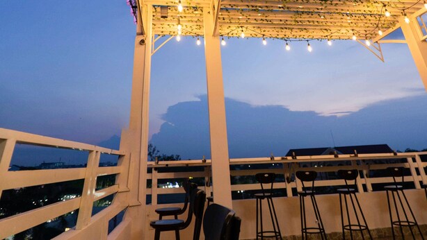 Uma área de estar externa com pérgola adornada por luzes de cordão e vista para o horizonte da cidade.