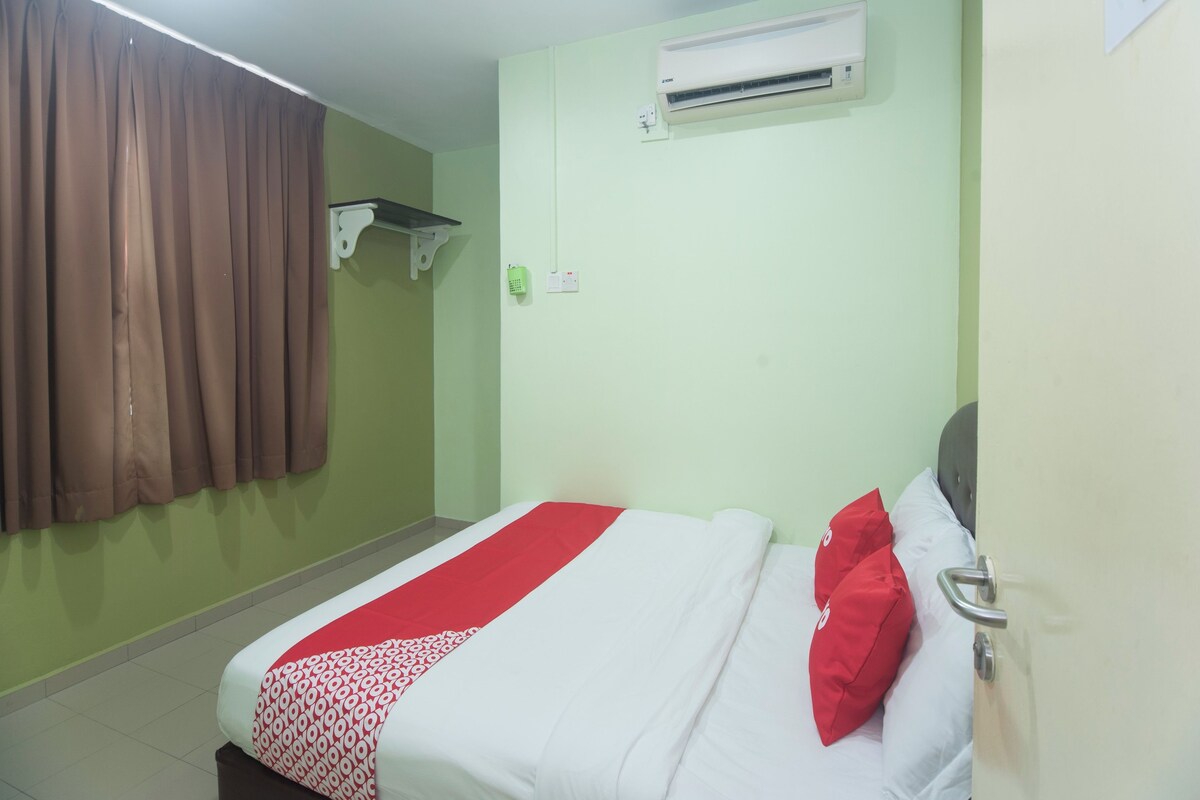 Quarto de hotel com cama, ar condicionado fixado na parede, cortina e prateleira.