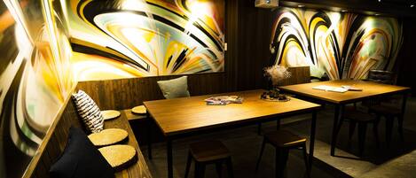 Um restaurante moderno com mesa e cadeiras de madeira, um banco com almofadas e arte abstrata nas paredes.