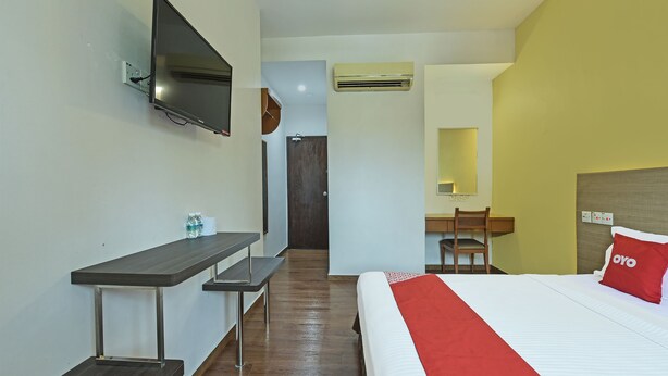 Quarto de hotel com cama, escrivaninha, cadeira, televisão e ar condicionado.