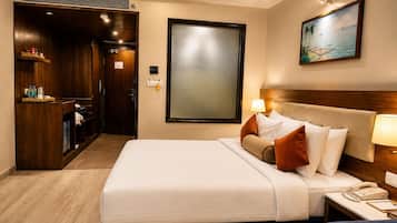 Quarto de hotel com cama, mesa de cabeceira, abajur e um quadro na parede.