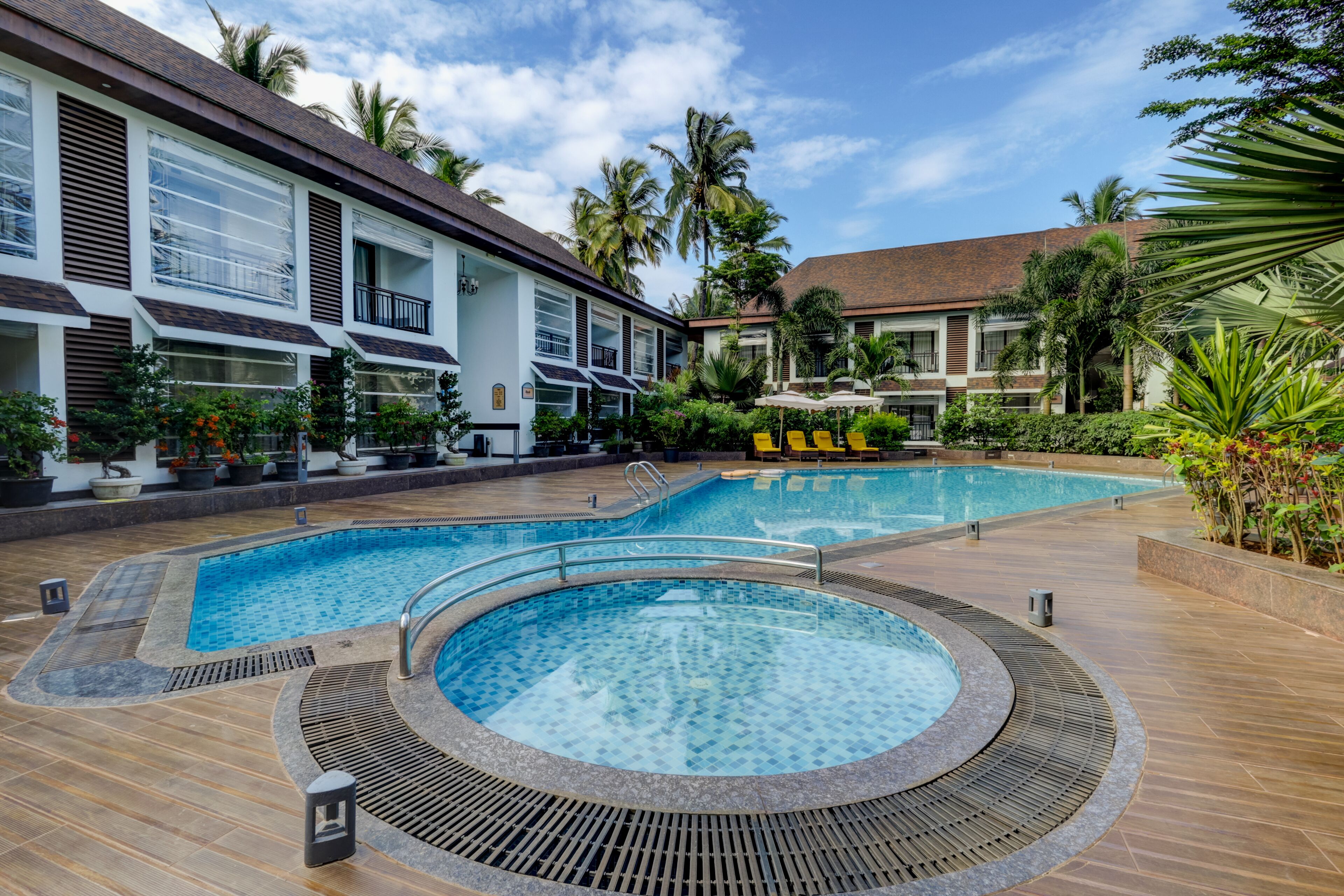 Um hotel com piscina, área de estar ao ar livre e palmeiras.