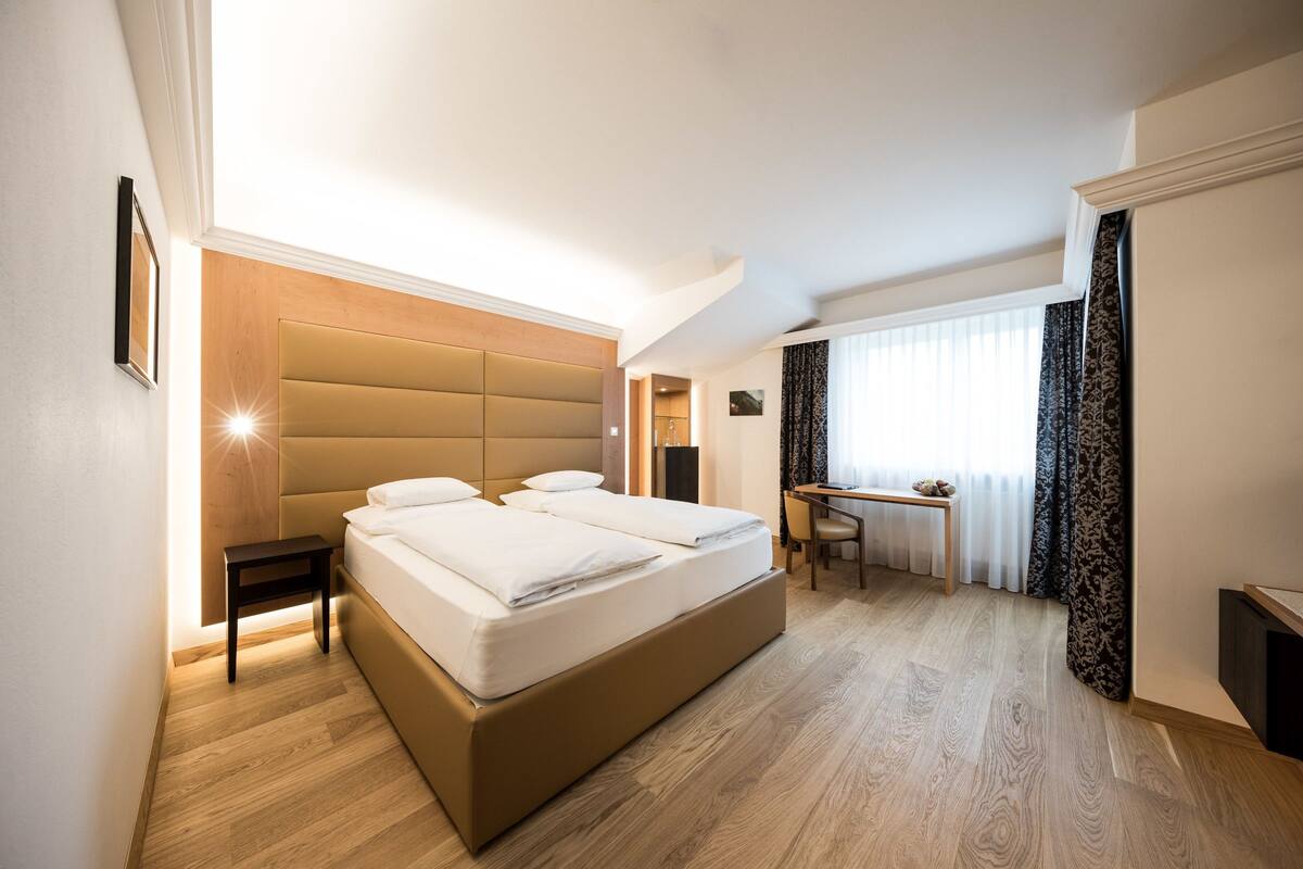 Quarto de hotel moderno com uma cama grande, uma escrivaninha e uma cadeira.