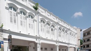 Um edifício branco em estilo colonial com janelas em arco e telhado plano.