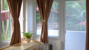Quarto com janela, cortinas, um vaso com planta e radiador.