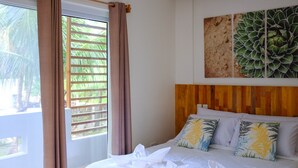 Quarto de hotel com cama, janela com persianas e uma planta na parede.