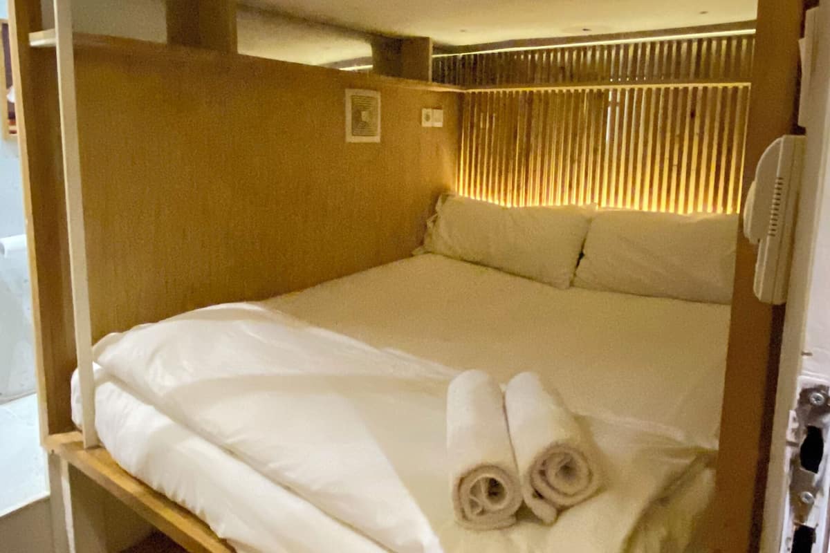 Uma cama beliche com roupa de cama branca e toalhas enroladas.