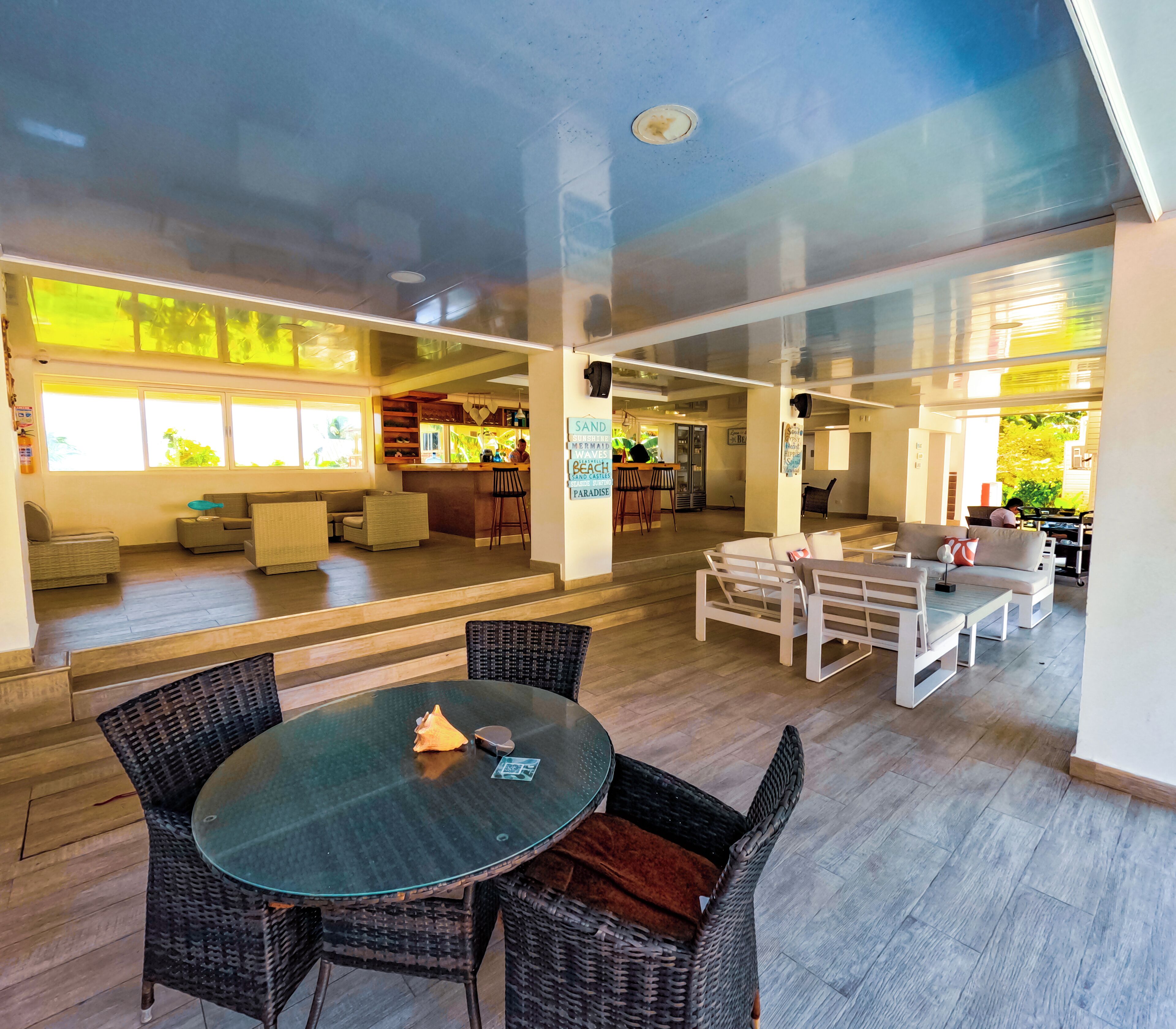 Um espaço interior moderno com teto de vidro, mobiliário de vime e área de bar.