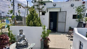 Pátio com estátua de Buda, plantas em vasos e área de estar.