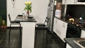 Uma cozinha compacta com uma ilha central, geladeira, fogão e pia.
